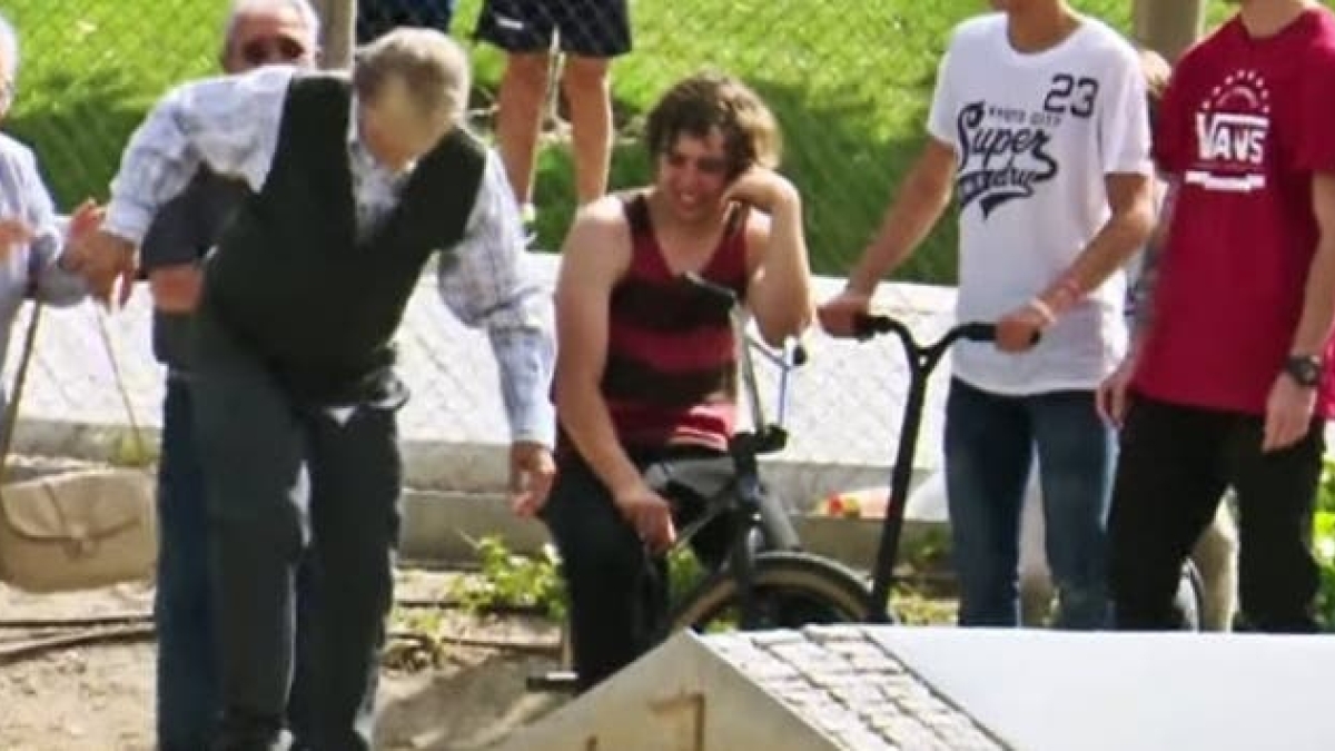 An old man, bent over crooked, painfully comes up on a group of skaters ...
